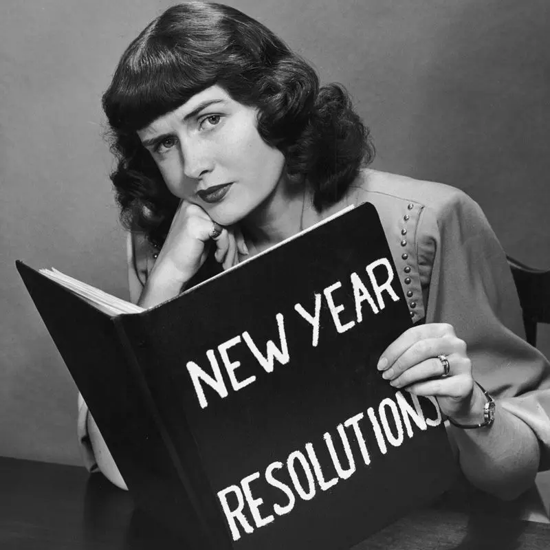 circa 1955: Studio ata o se tamaitai fa'amata'u ma lona auvae o lo'o i lona lima, o lo'o uuina se tusi tele ua fa'aigoaina 'New Year Resolutions'. (Ata na saunia e Harold M. Lambert/Lambert/Getty Images)