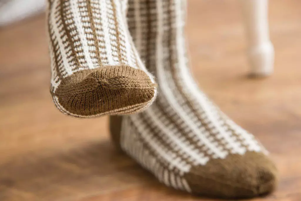 Apprenez à tricoter des chaussettes avec un simple motif de mailles coulées en deux couleurs pour créer un effet de faux carreaux !