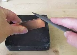 Najprv použite polkruhový pilník tak, že položíte kus, ktorý sa má pilovať, na gumený blok alebo iný stabilný povrch, ako je znázornené.